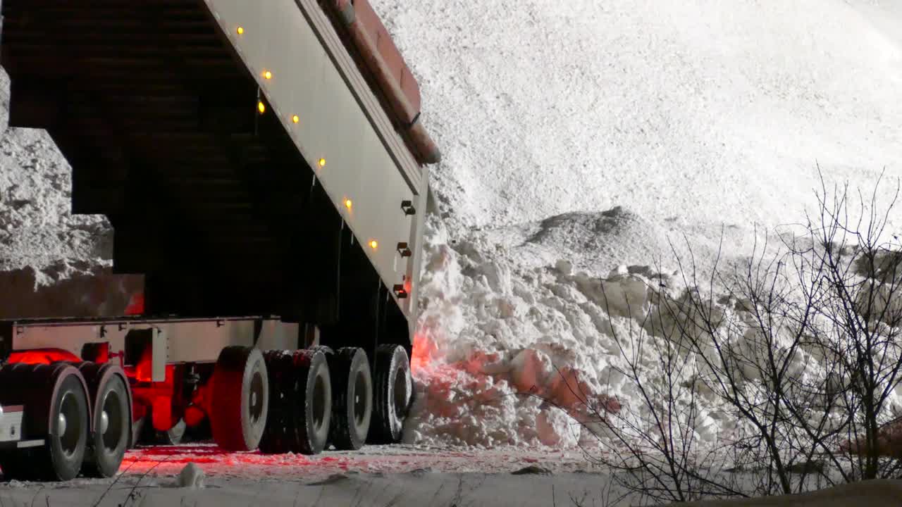 Premium stock video - A large tip truck unloads snow and ice at one of ...