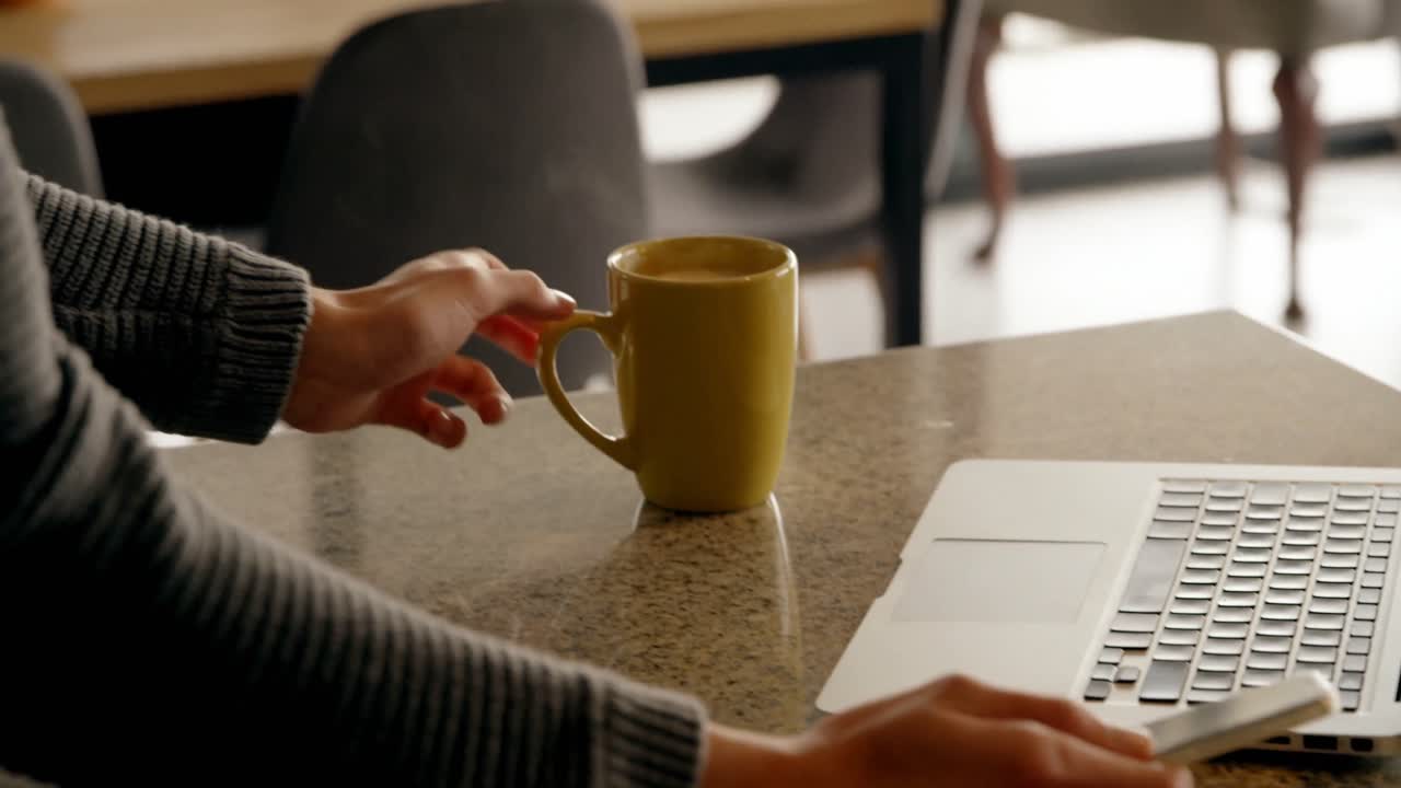 Premium stock video - Man having coffee while using mobile phone 4k