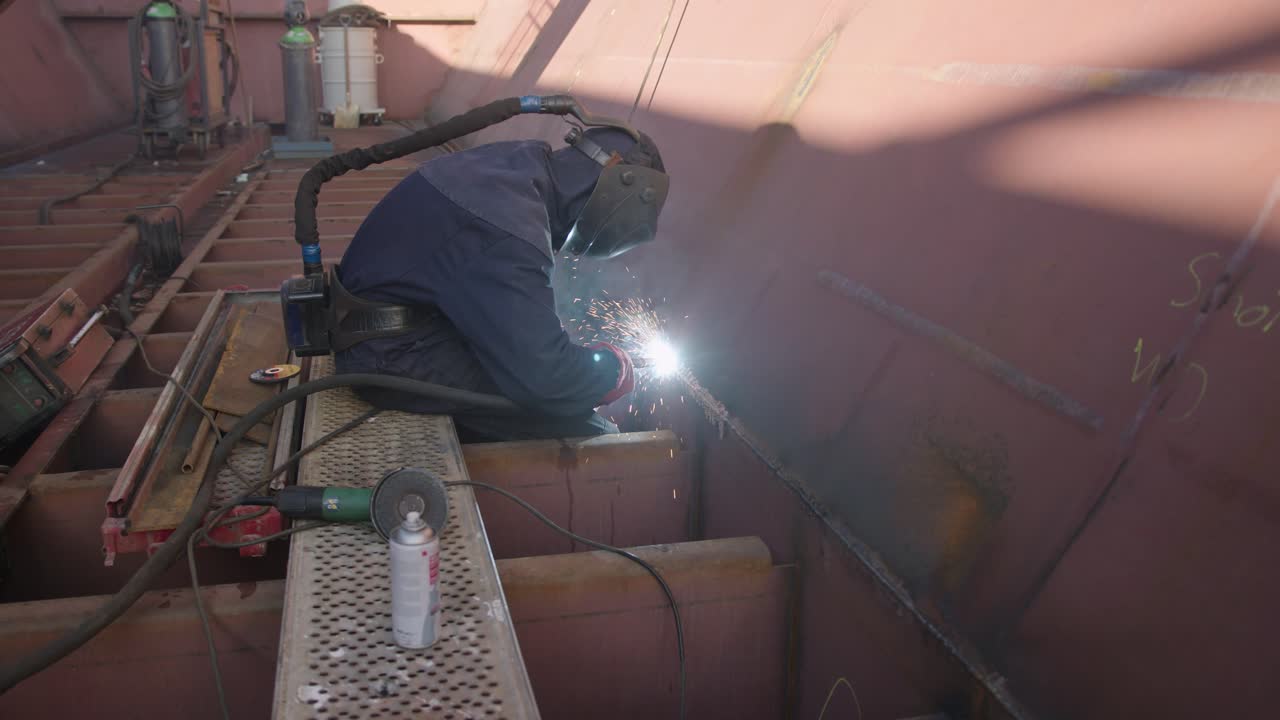 Close up of professional worker welding inside large metal container ...