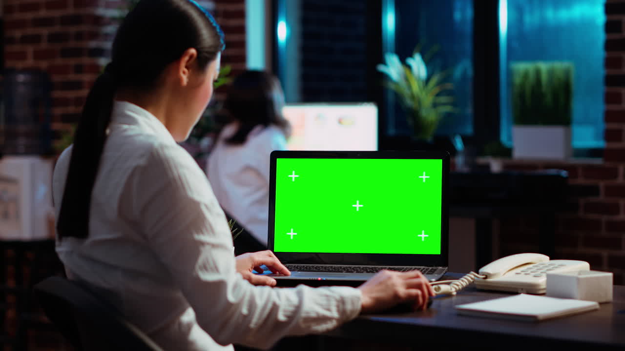 Worker looking over green screen laptop display, researching data ...