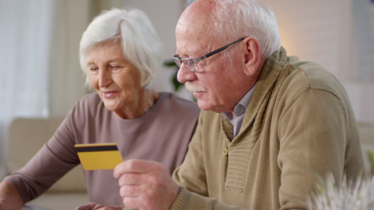 Elderly Couple Making Online Payment Using Credit Card And Laptop ...