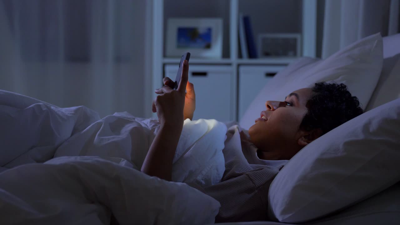 Premium stock video - Woman with smartphone in bed at home at night ...