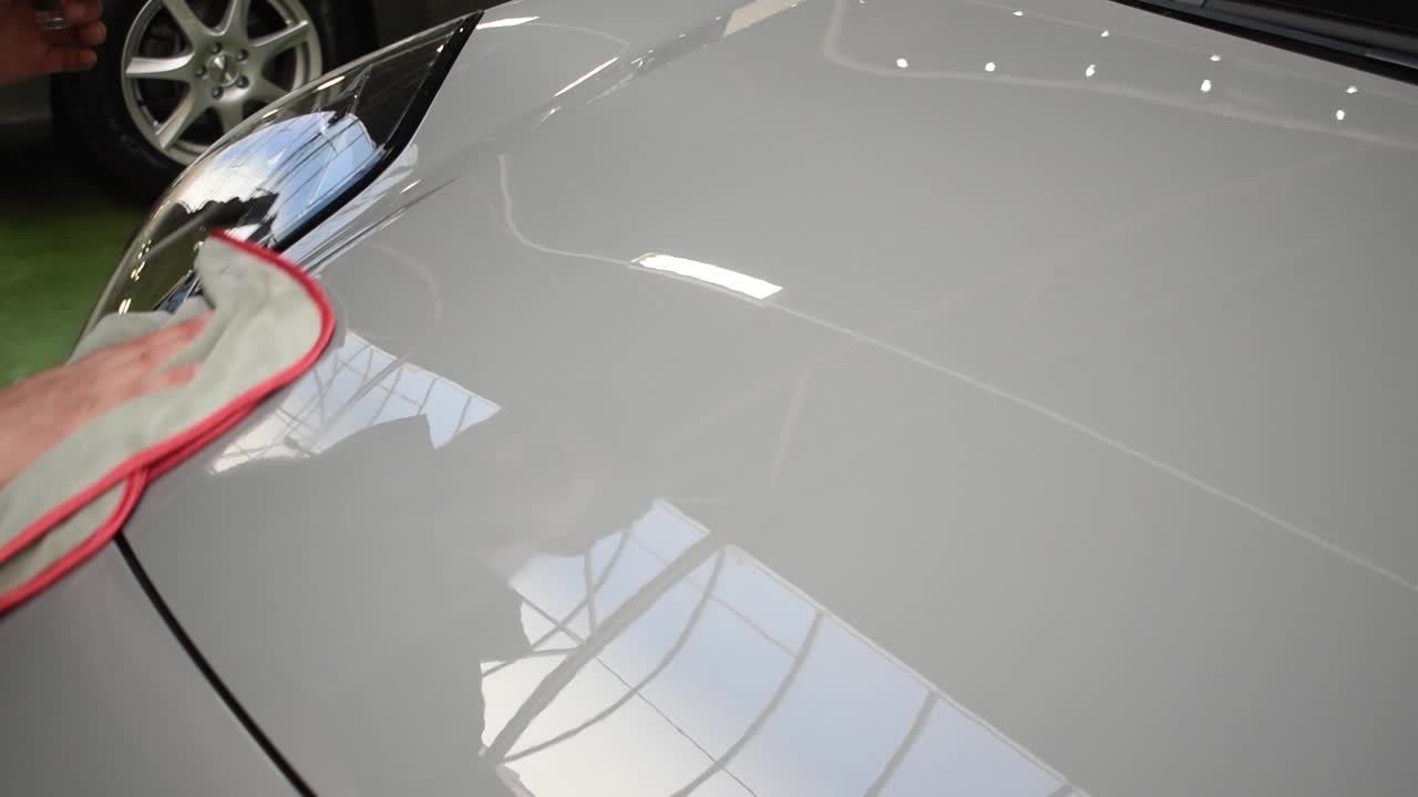 Timelapse male hand applying ceramic coating shiny grey car hood ...