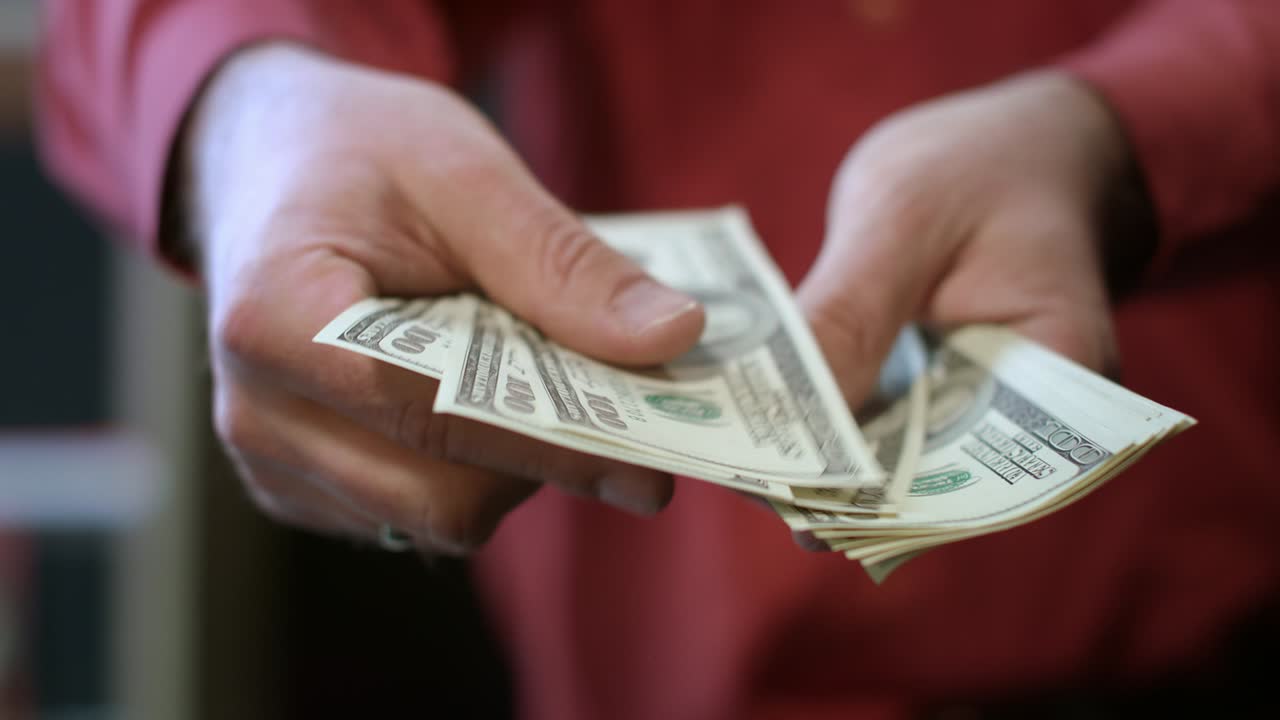 Premium stock video - Man counting dollar bills. Close up of male hands count money cash