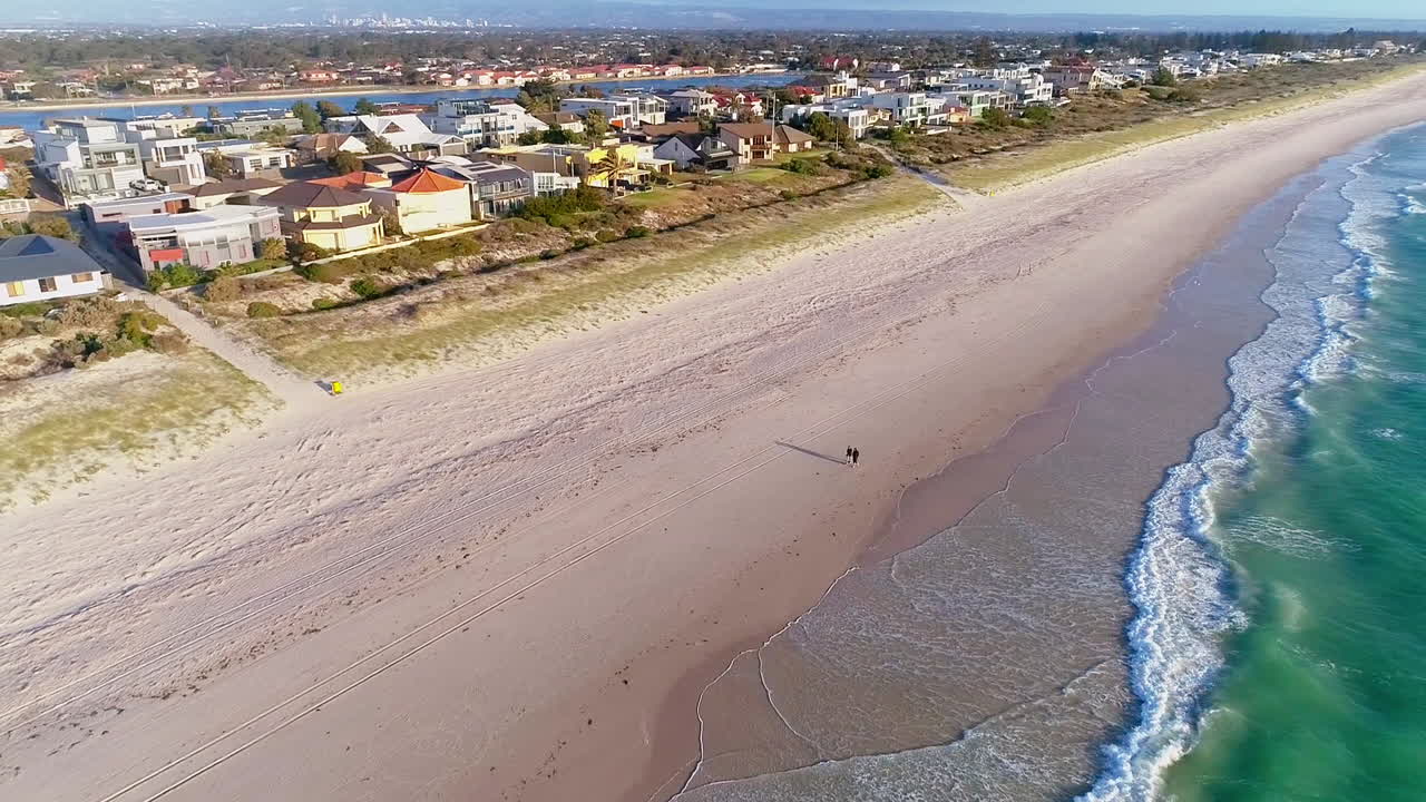 Two people walking along the beach in Tennyson in Adelaide, South ...