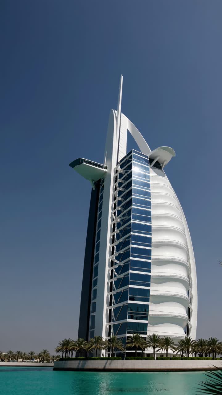 A low-angle shot of a modern sail-shaped skyscraper against a clear sky ...