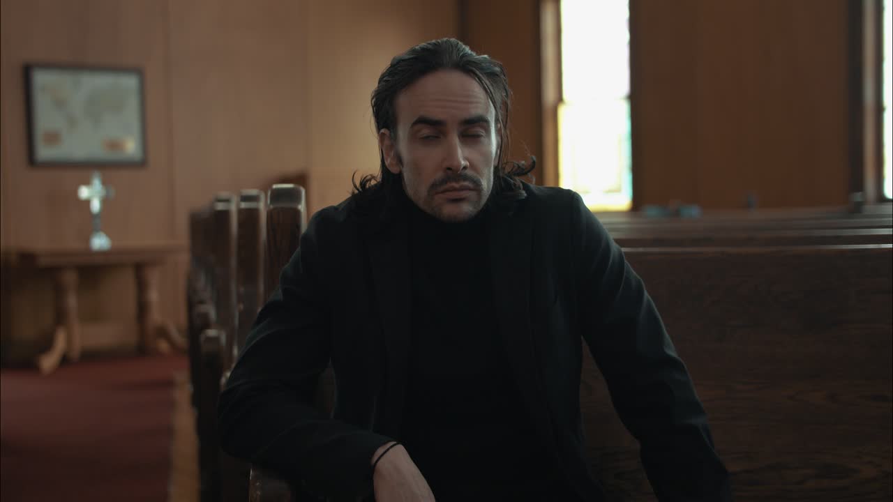 Stressed, anxious, emotional, sombre man in black suit sitting in pew ...