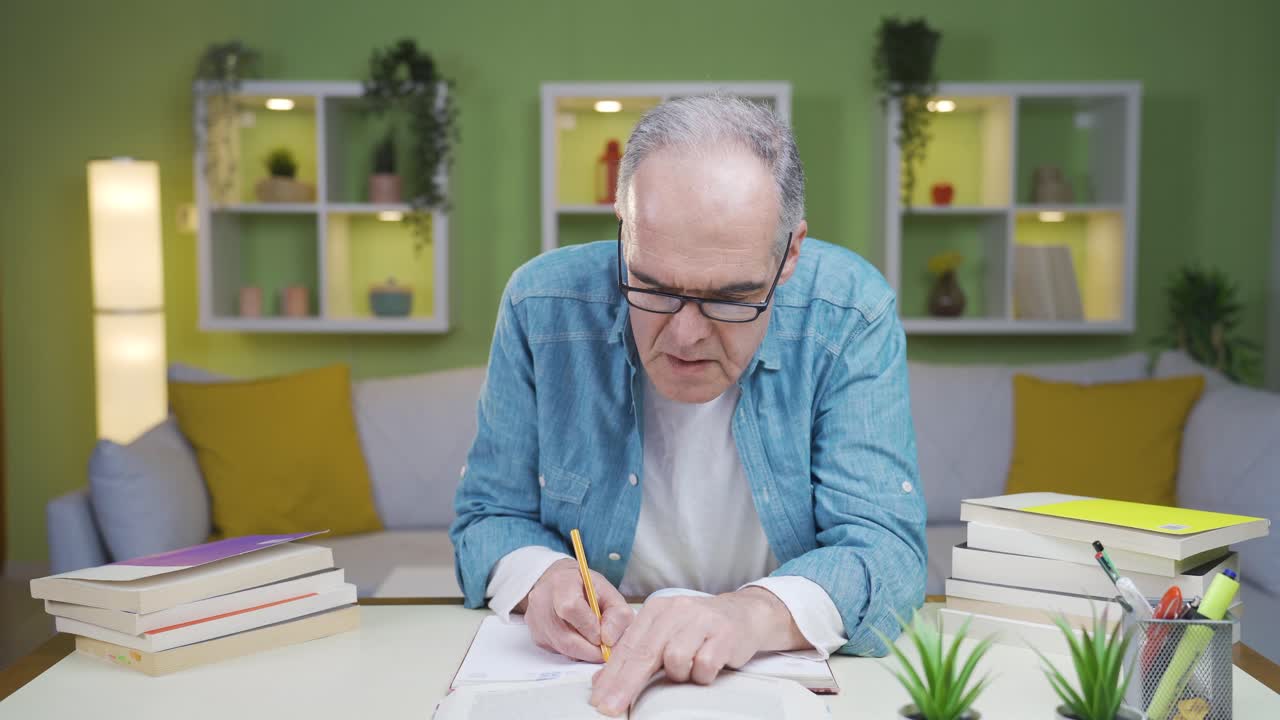 Old man taking notes about the book he's reading. Premium Stock Video ...