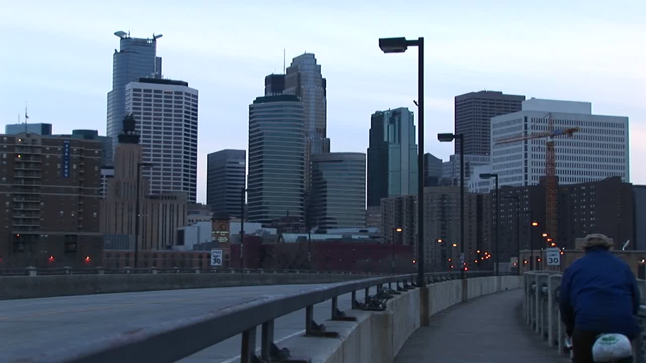 Premium stock video - Cars and a bicyclist cross a bridge into the city