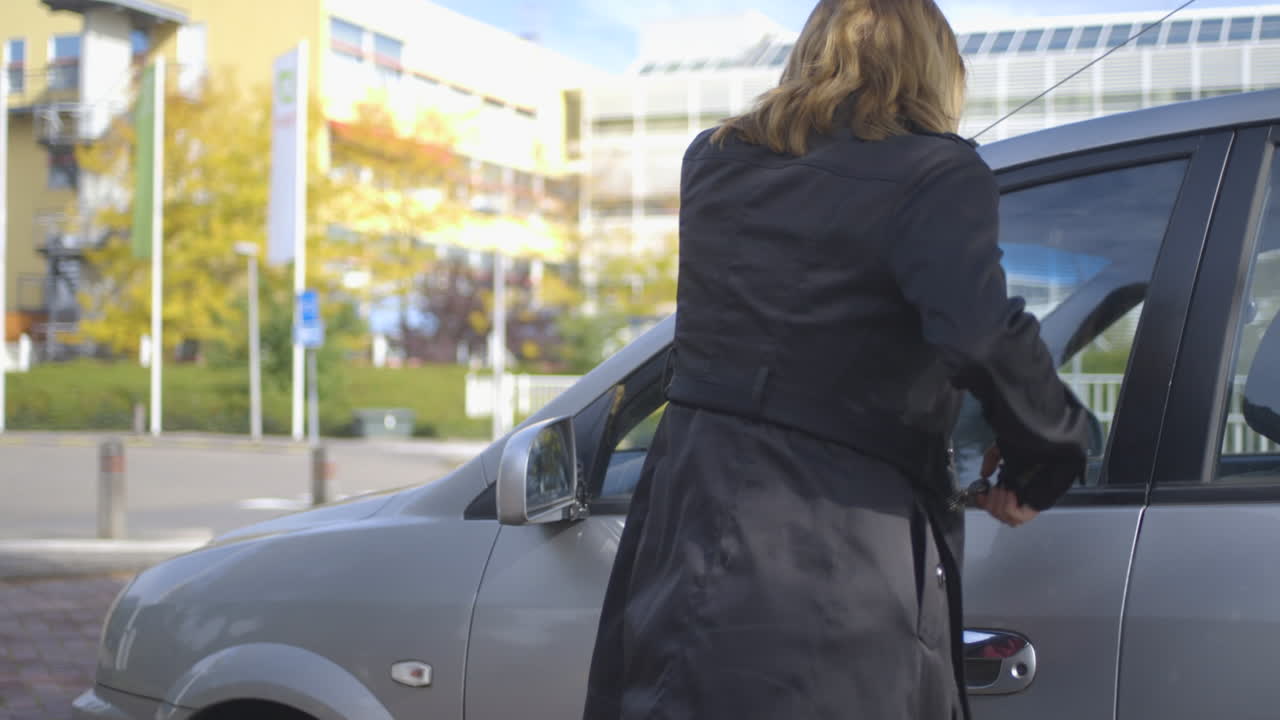 Premium stock video - A buzzed woman steps into the drivers seat of her car
