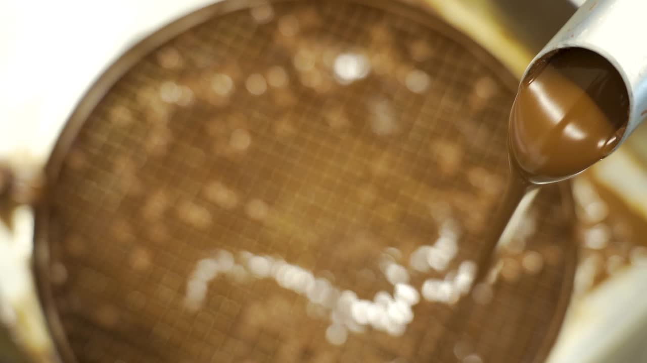 Premium stock video - Melted chocolate flowing out of a pipe into a ...