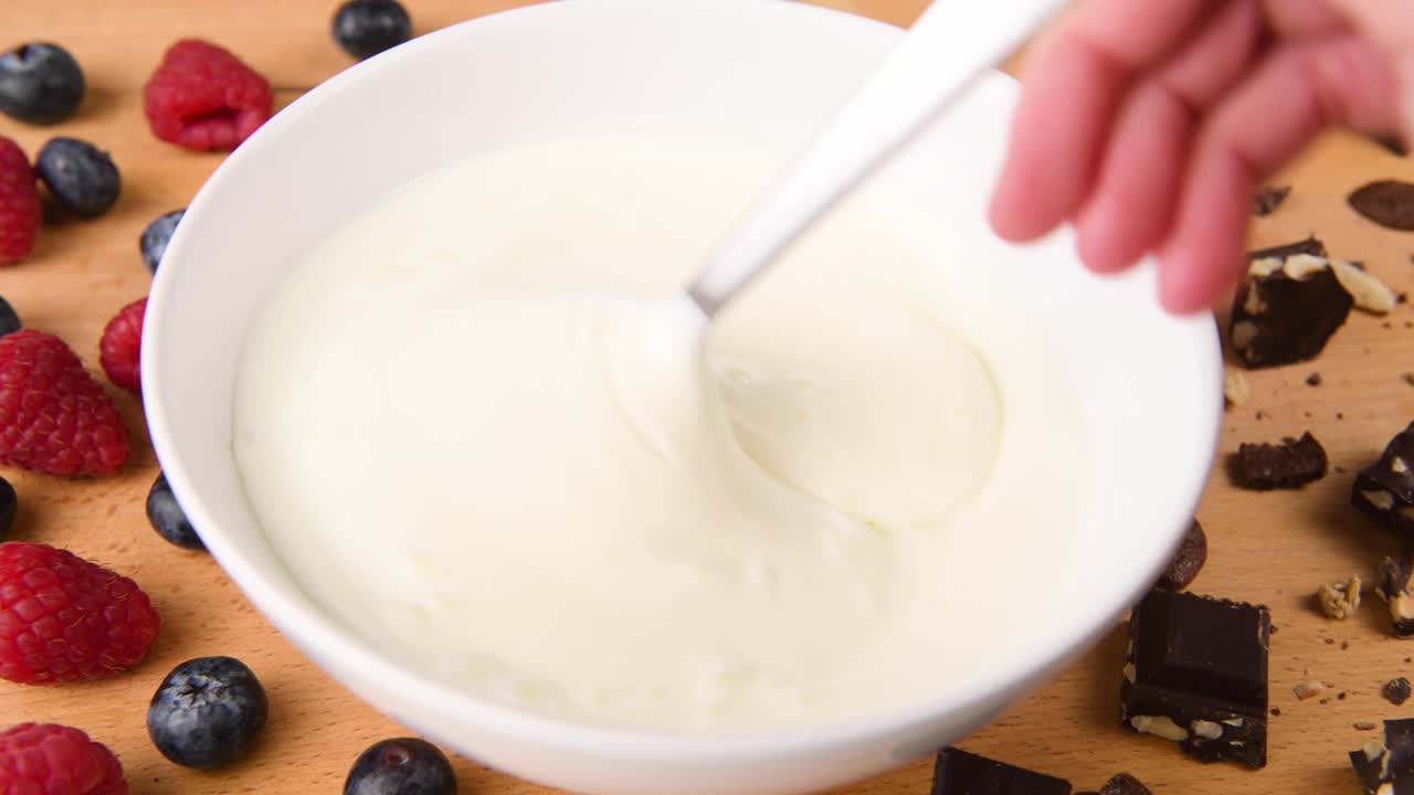 Premium stock video - Stirring a bowl of plain yogurt
