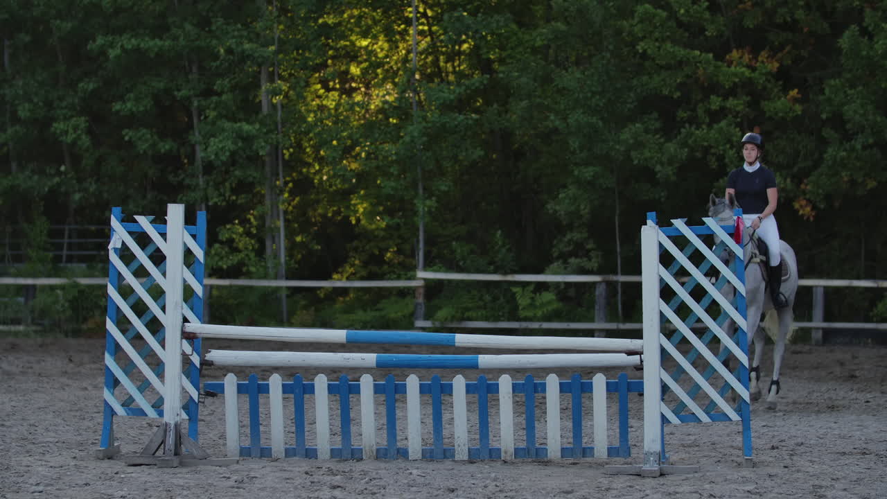 A Woman Jockey In A Black And White Suit On A Horse Makes A Jump Over The Barrier. SLOW MOTION ...