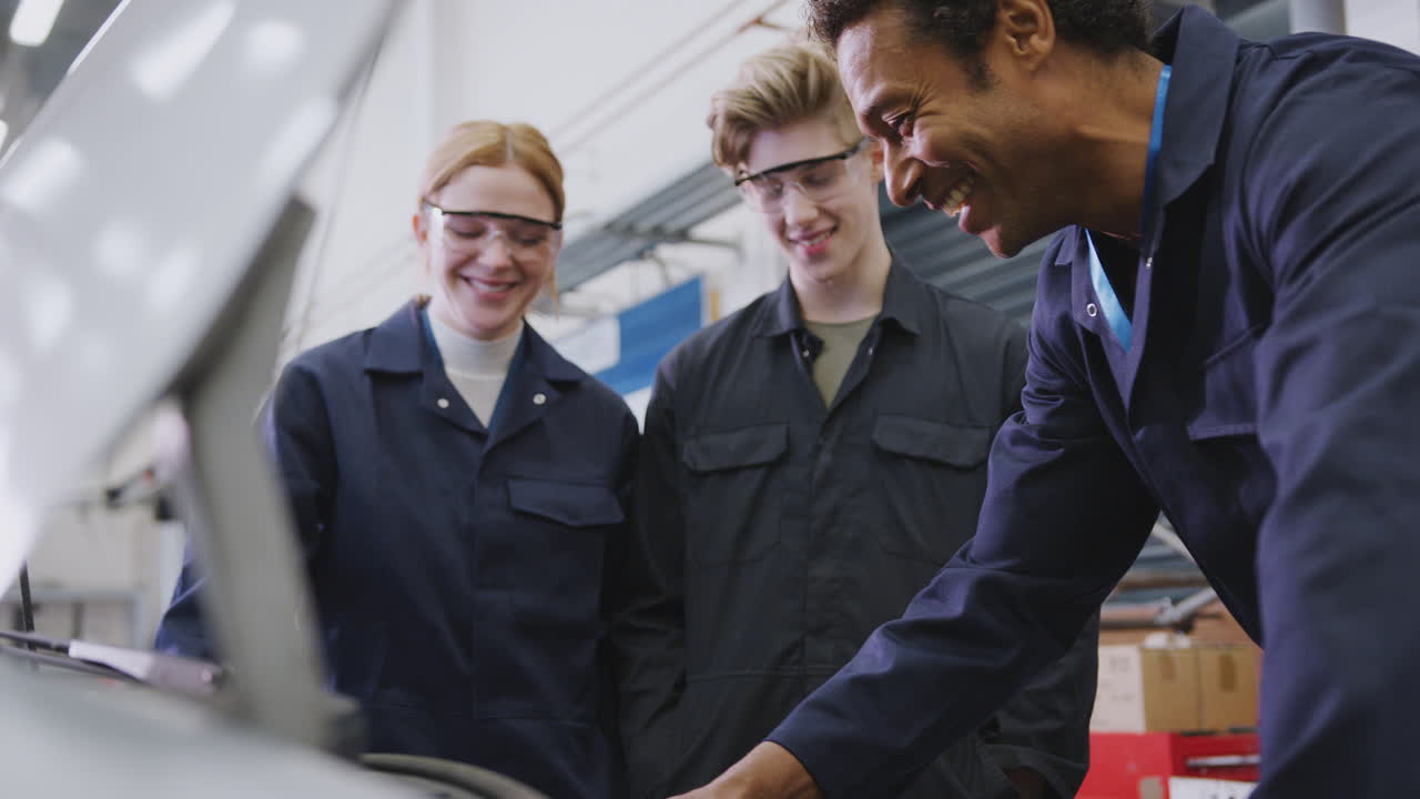 Premium stock video - Male tutor with students looking at car engine on ...