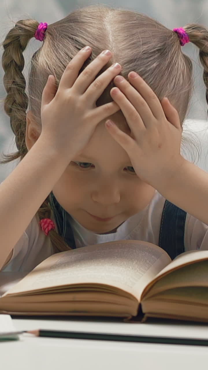 Slow motion: cute happy little child with plaits tired of doing home ...