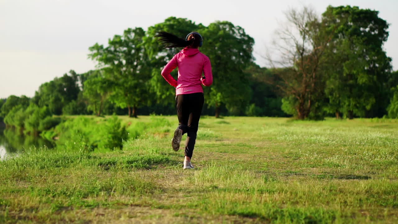A morning jog in the park near the pond in the sunny rays of dawn, the ...
