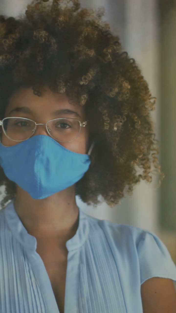 Animation of light spots over african american woman with face mask ...