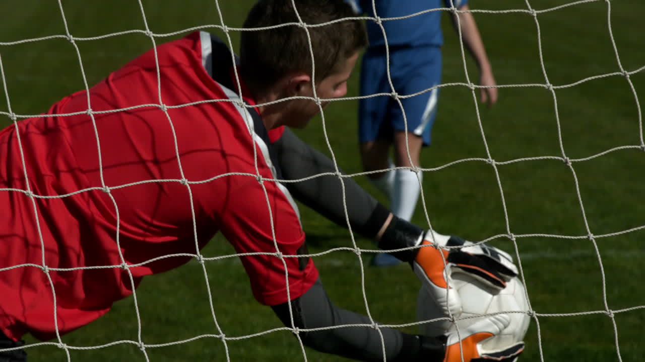 Premium stock video - Goalkeeper in red saving a goal during a game