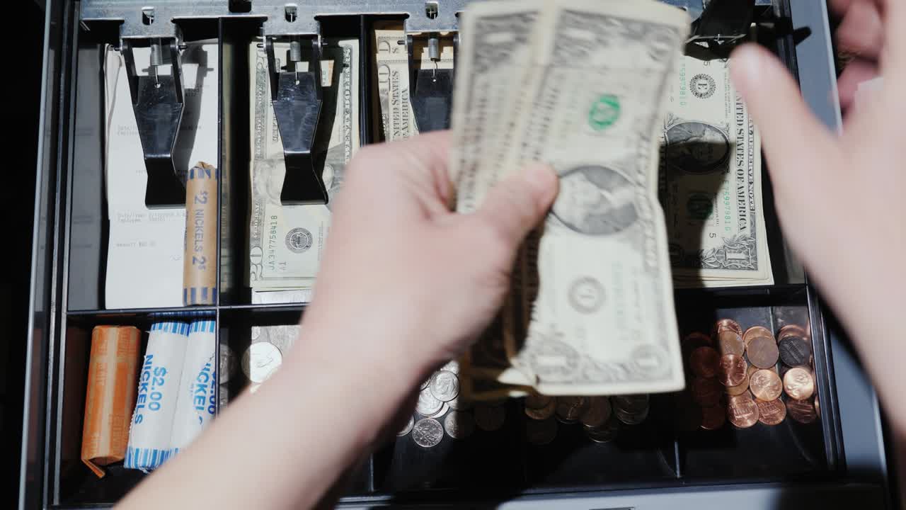 A woman cashier works with the cashier. He puts money and takes the ...