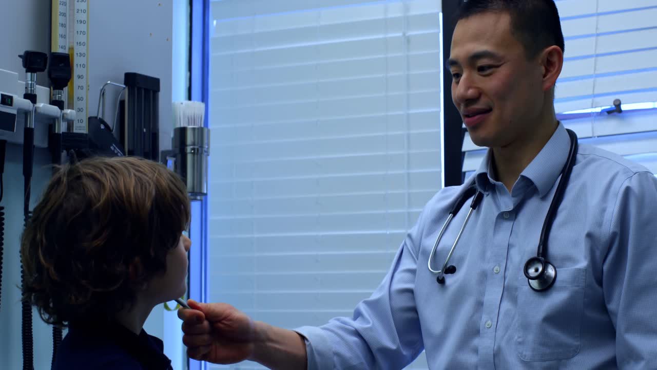 Side view of young asian male doctor showing tuning fork to caucasian ...