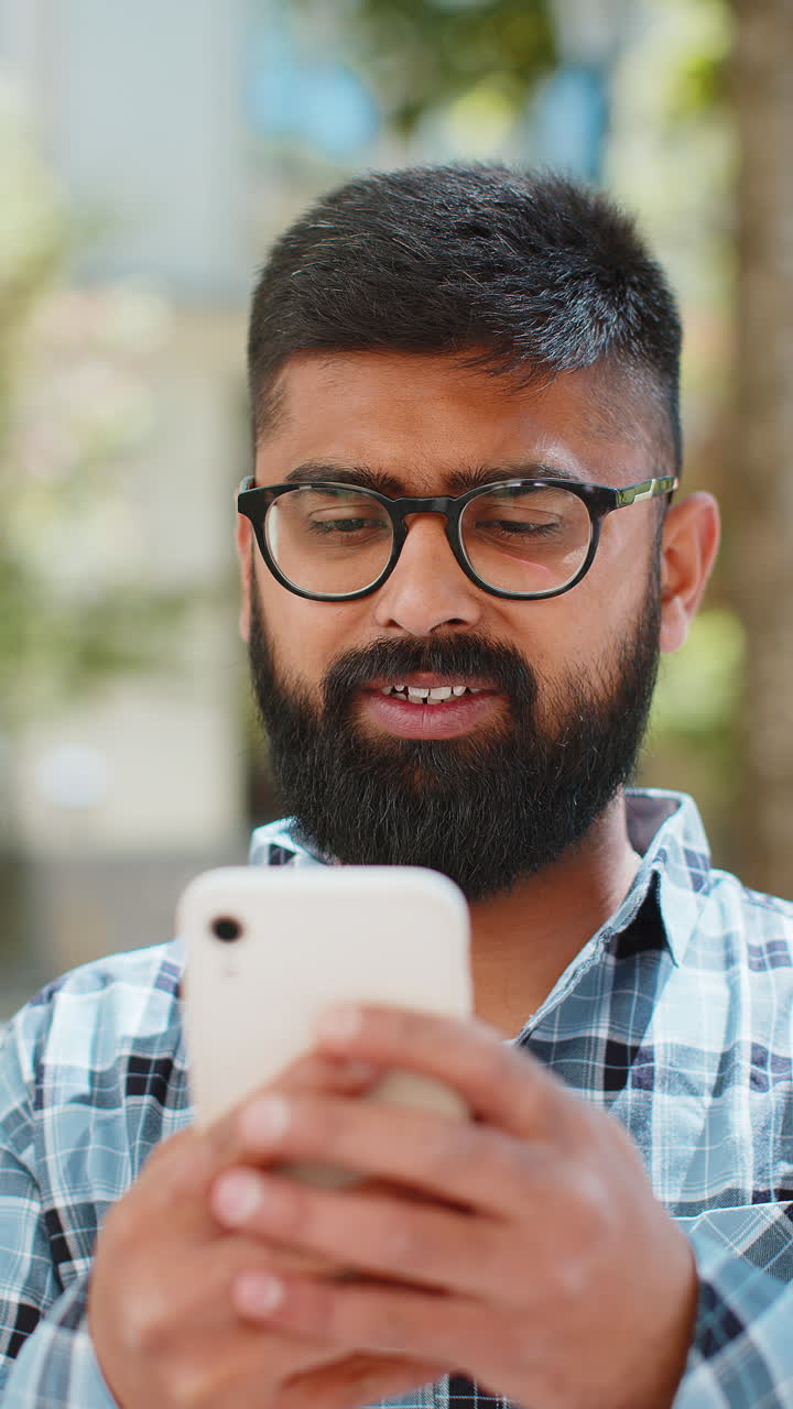 Premium stock video - Indian bearded man using smartphone typing text messages in social media ...