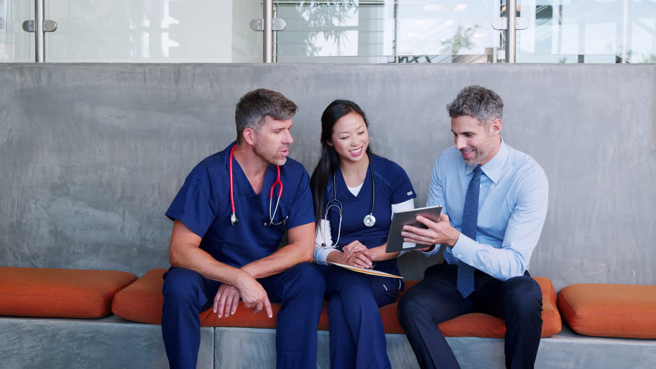 Three doctors checking information on a tablet in hospital | Premium ...