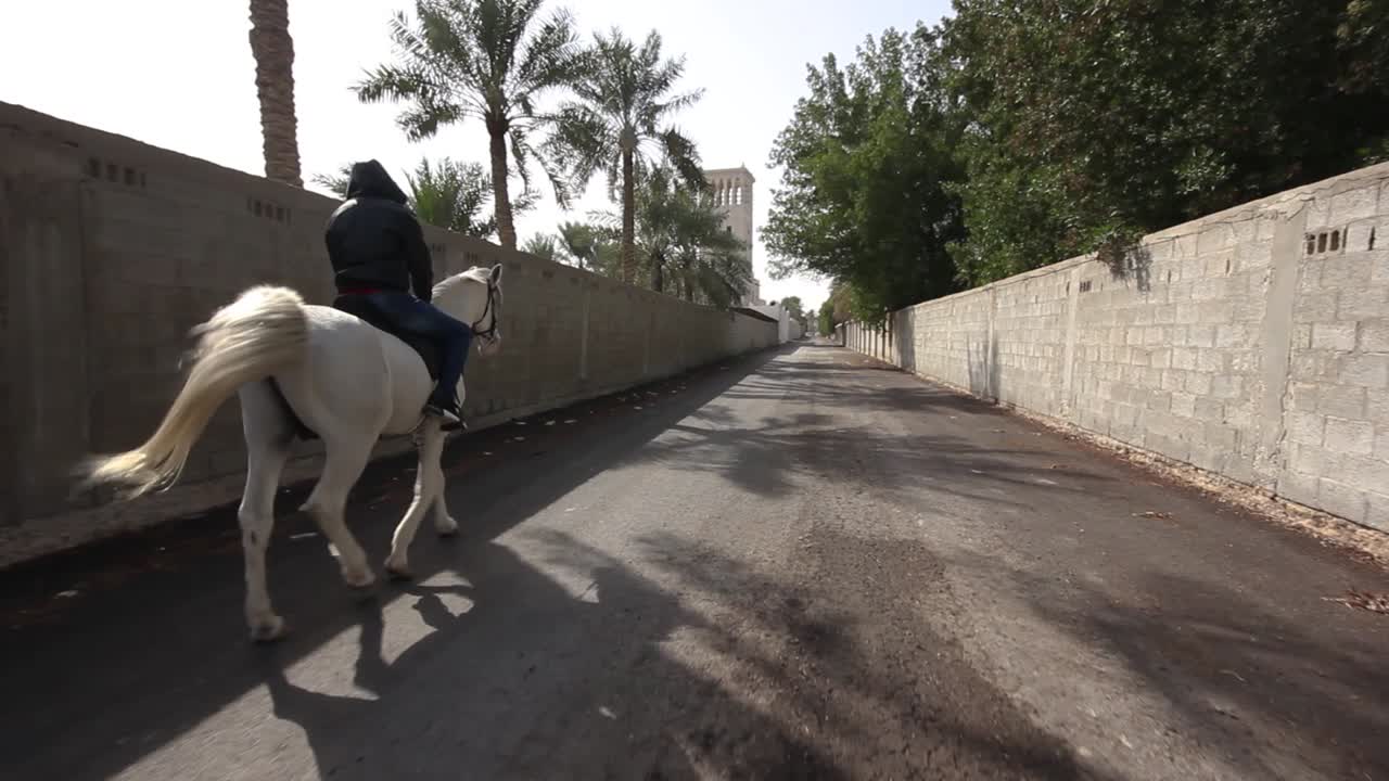 Premium stock video - A hooded western man riding a white arabian horse ...